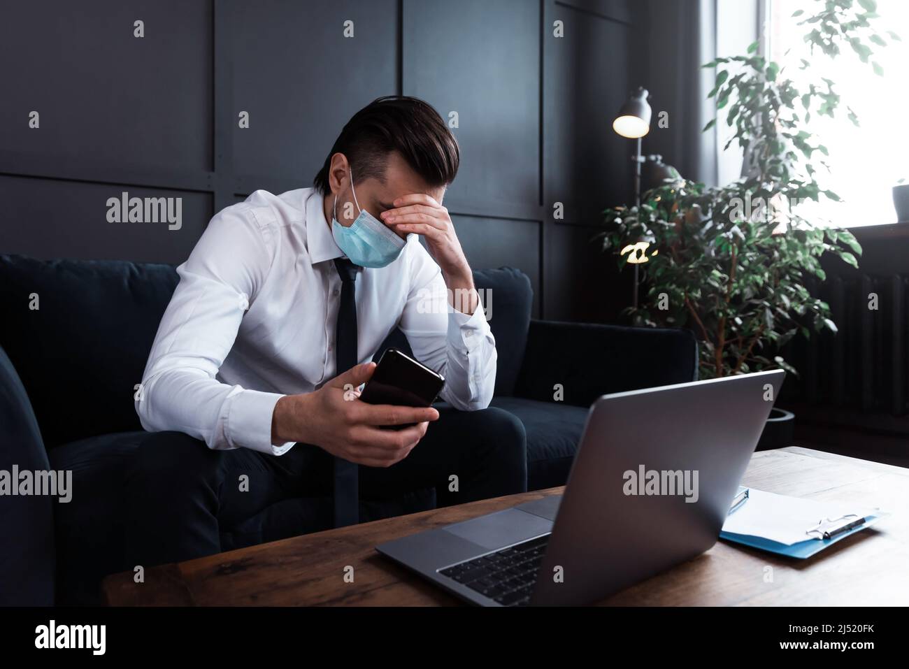 Tired businessman with a sickness symptoms wearing prevention mask at ...