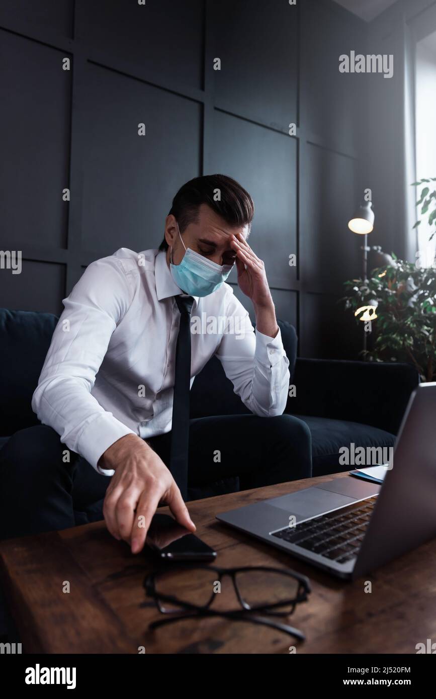 Tired businessman with a sickness symptoms wearing prevention mask at ...