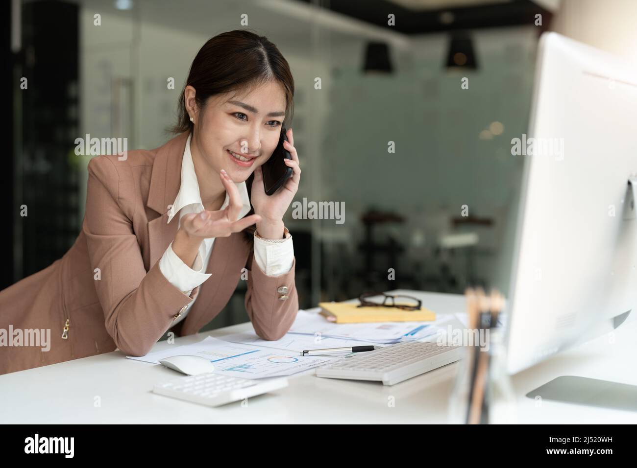 Asian accountant using smartphone to call marketing consultants and ...