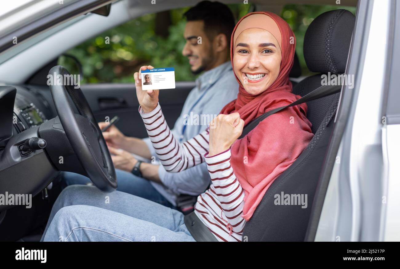 Glad muslim woman in hijab show driving license and fist in open door ...