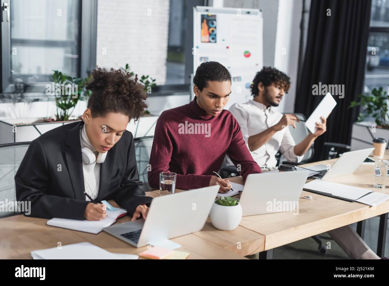 African american business people writing on notebooks near laptops and ...