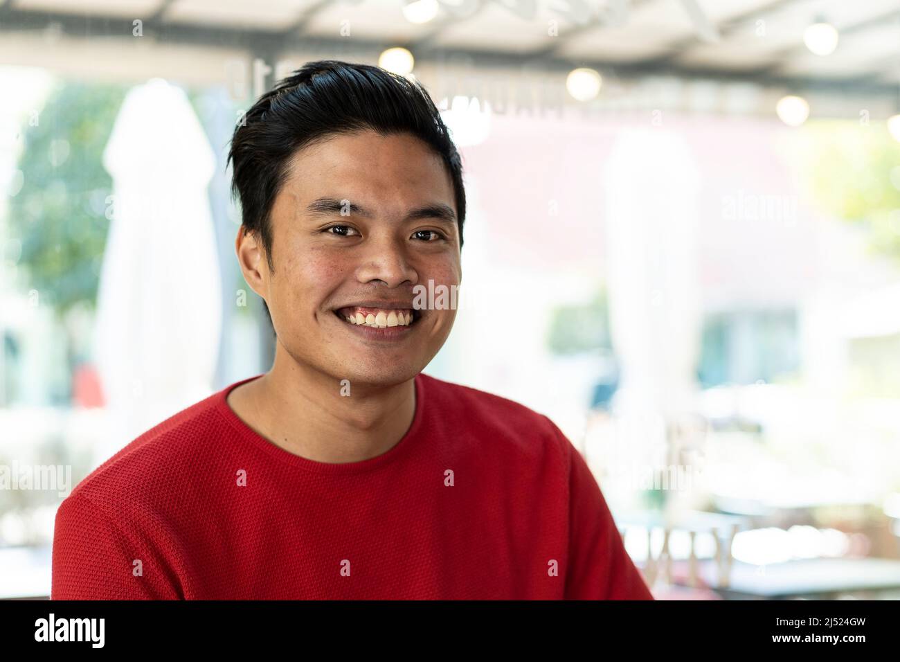 Young asian man smiling on camera indoor - Focus on face Stock Photo ...
