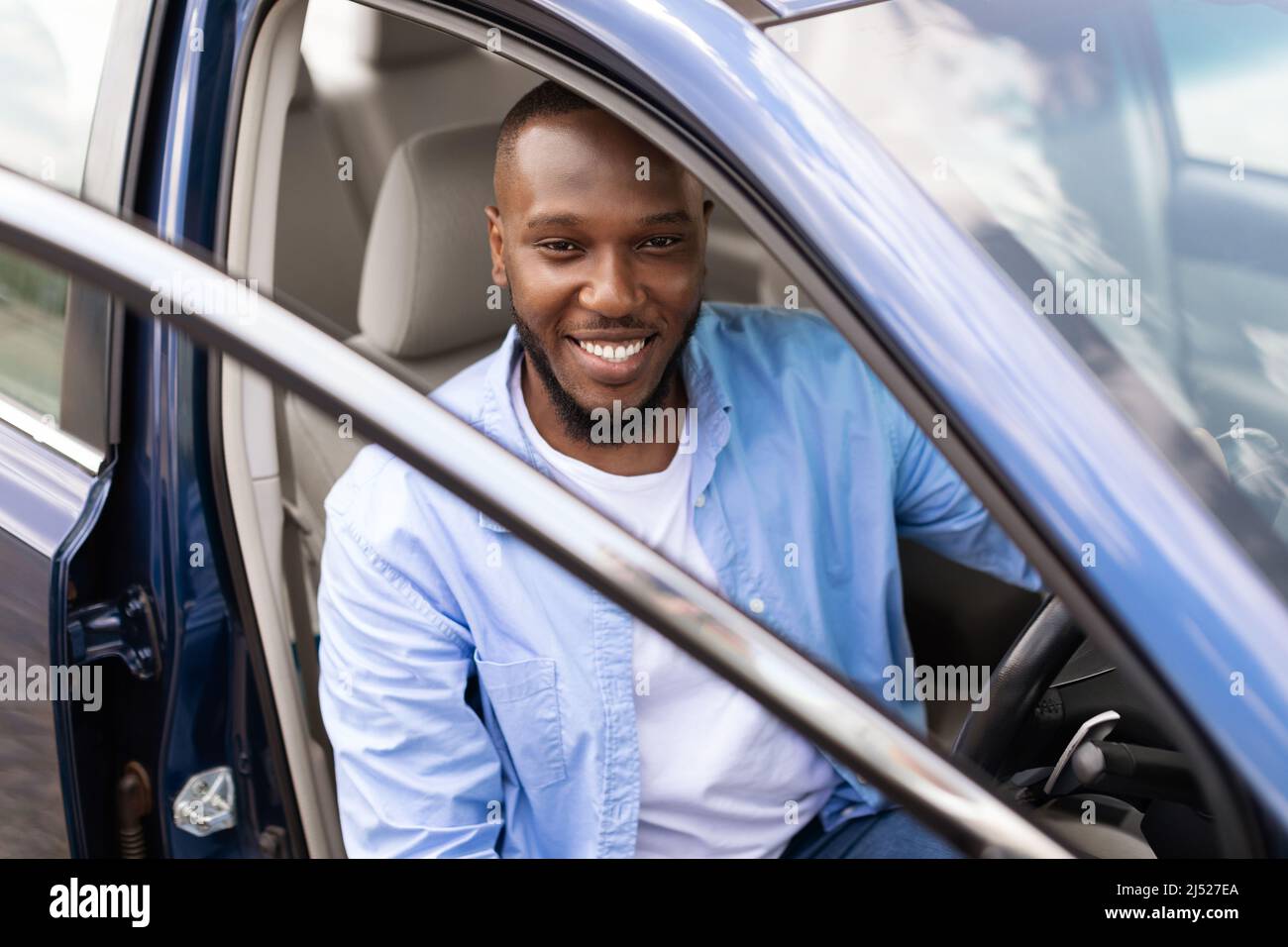 Smiling black man driving new car in the city Stock Photo - Alamy