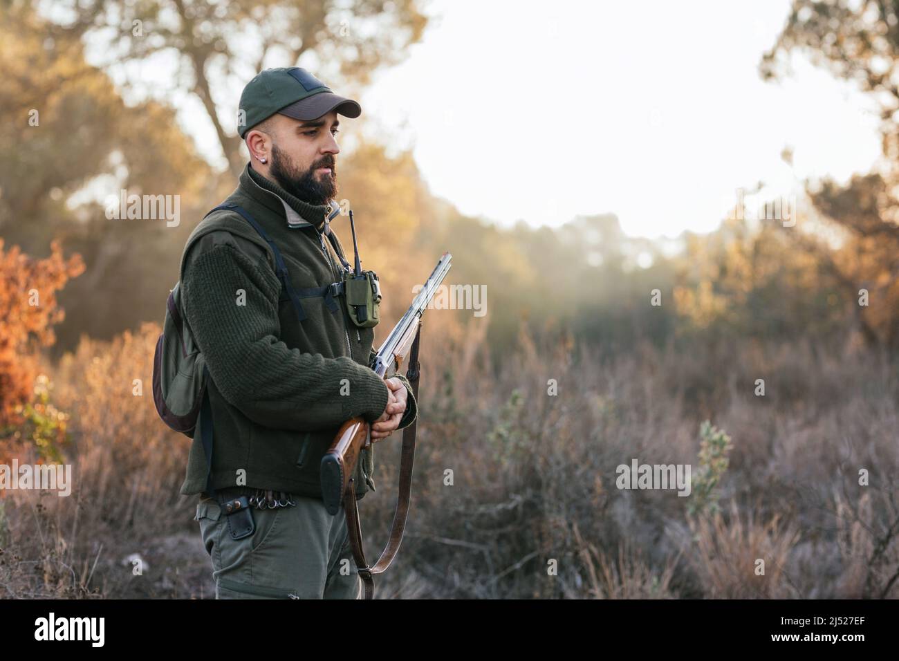 Adult man holding his gun in middle of nature looking down Stock Photo ...