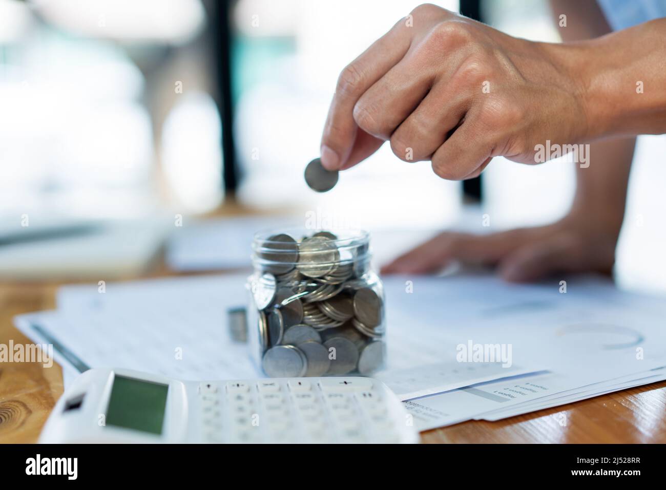 Hand dropping coins into a piggy bank hi-res stock photography and ...