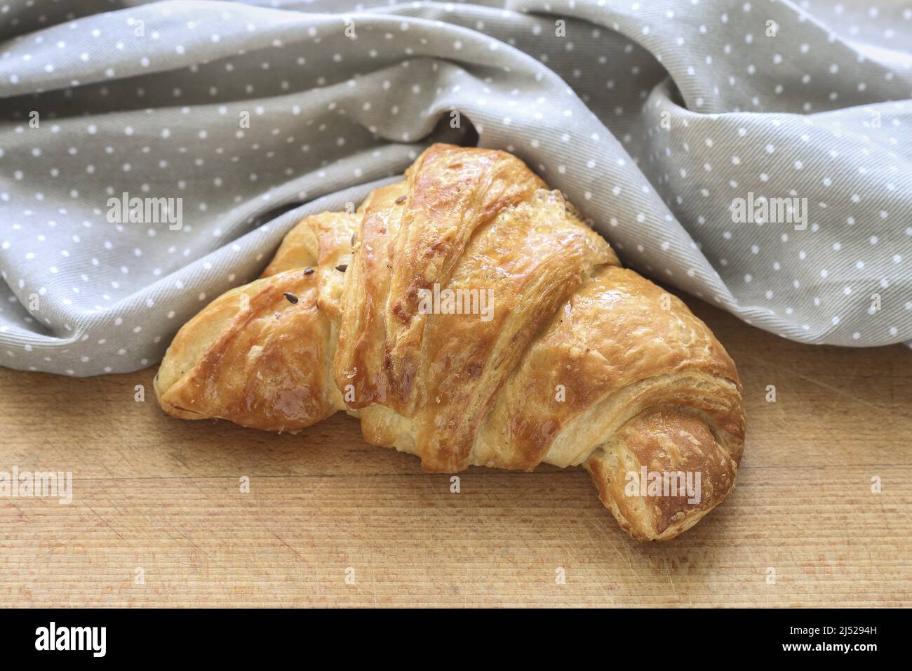 French croissant made of puff pastry on a wooden table. Breakfast time ...