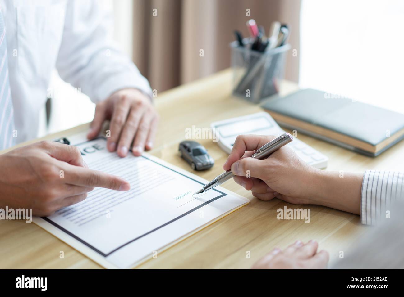 Insurance concept the male dealer suggesting his customer to sign the ...