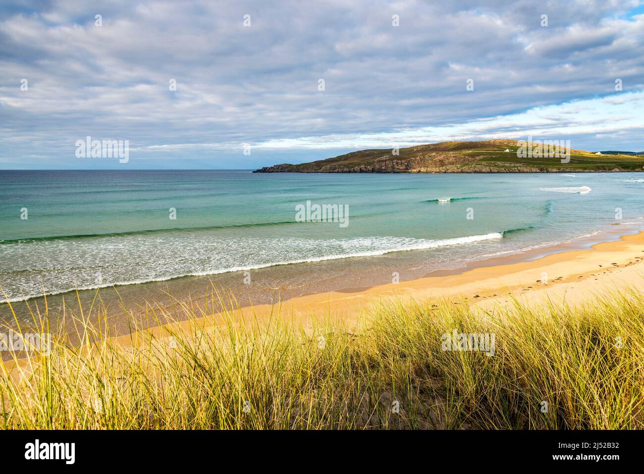 Sun shines on the vibrant turquoise sea and breaking waves by the empty ...