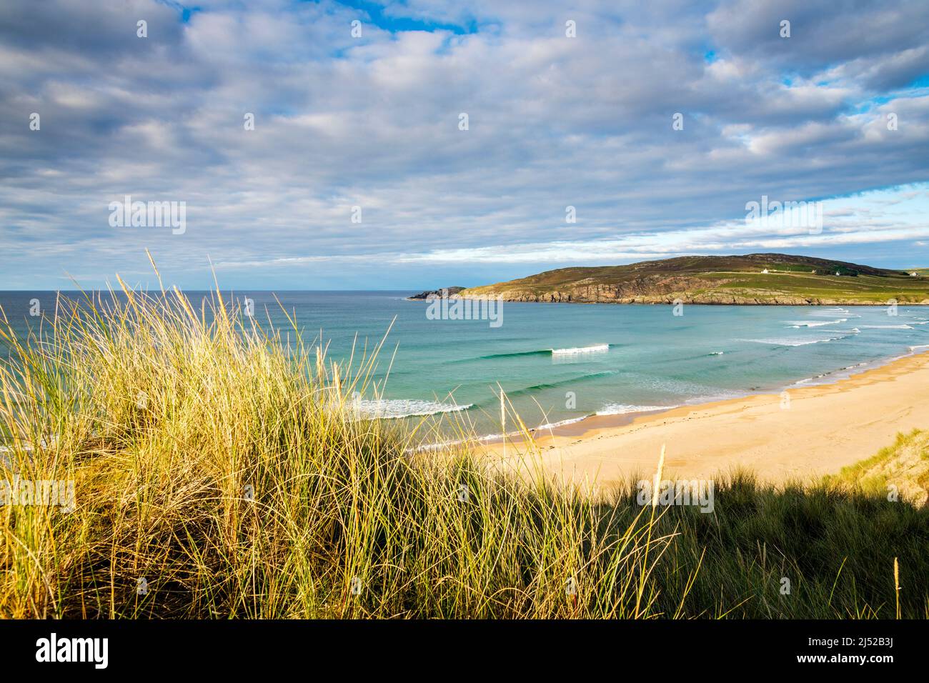 Sun shines on the vibrant turquoise sea and breaking waves by the empty ...