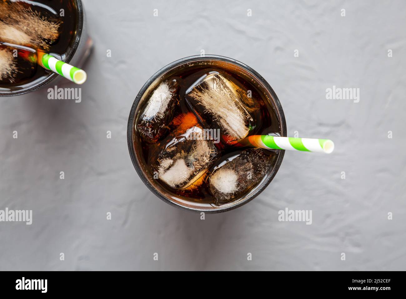 Cold Refreshing Dark Cola with Ice Cubes, Straws on a gray surface, top ...