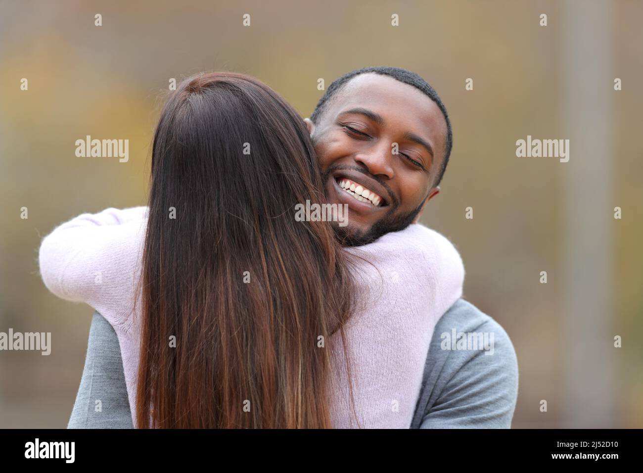 Front view portrait of a happy man with black skin hugging a friend ...