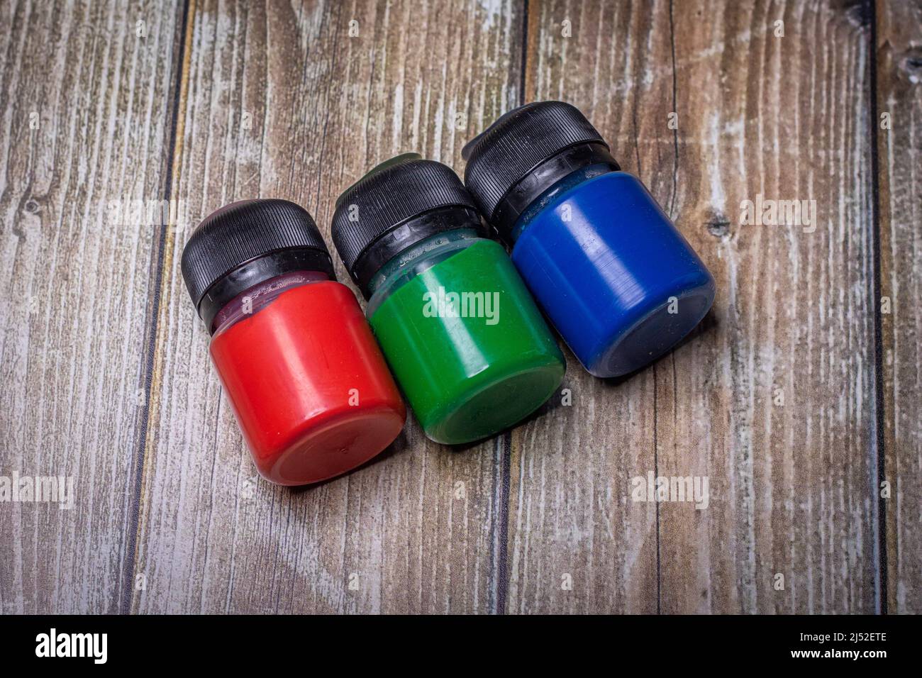 three small plastic paint bottles in the colors red, green and blue on ...