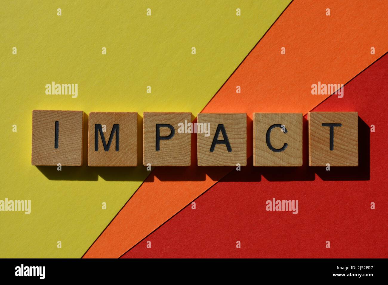 Impact, word in wooden alphabet letters isolated on red, orange, yellow ...