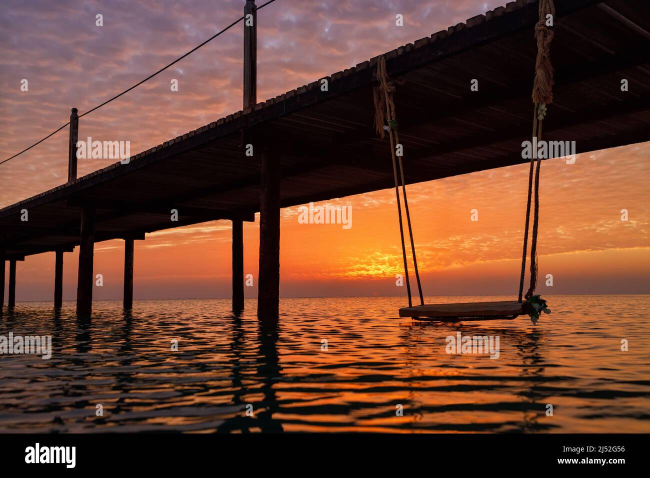 Wooden swing under the pontoon bridge at sunrise Stock Photo - Alamy