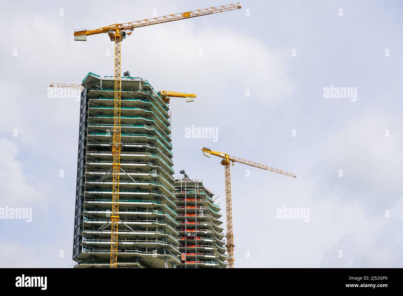 three yellow tower cranes and a fragment of the facade of an unfinished ...