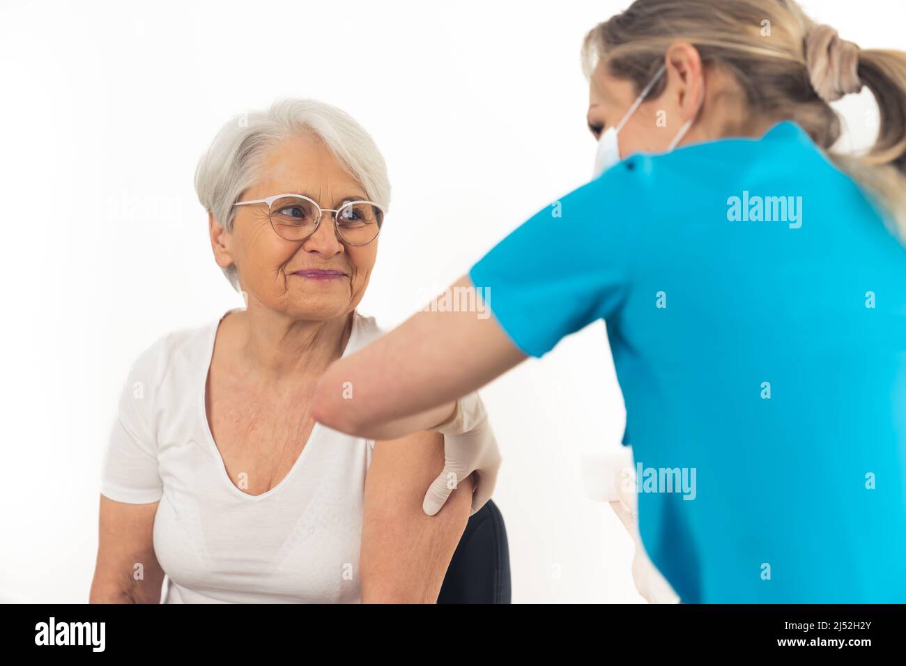 female doctor making vaccination on the senior woman shoulder ...