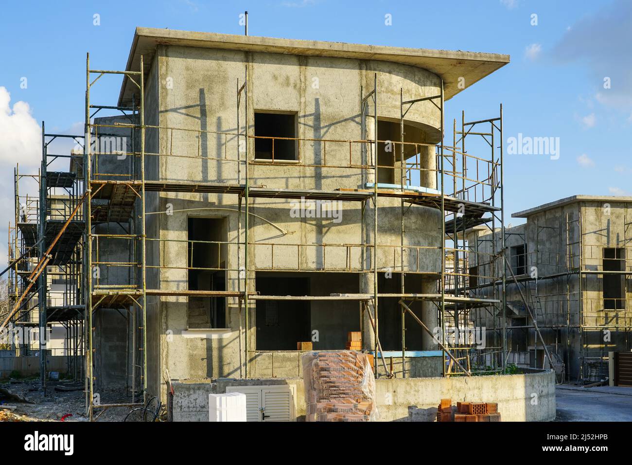 scaffolding around unfinished concrete frame of private house under ...