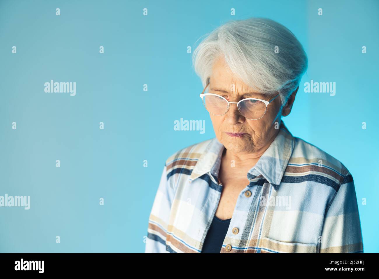 senior European woman worried about her health problems copy space blue ...