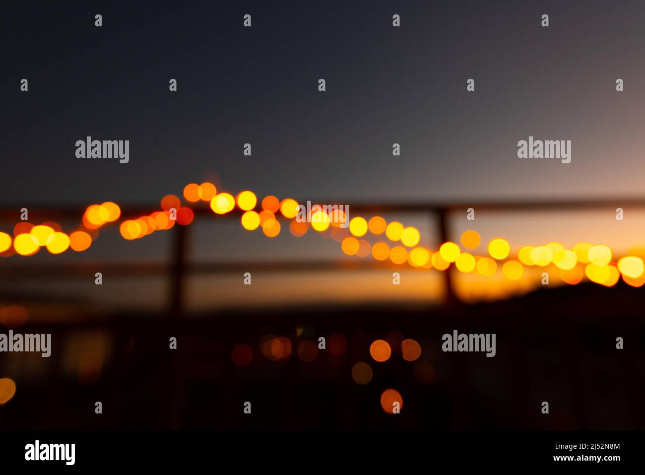 Out of focus christmas lights on the railings of a balcony at night ...