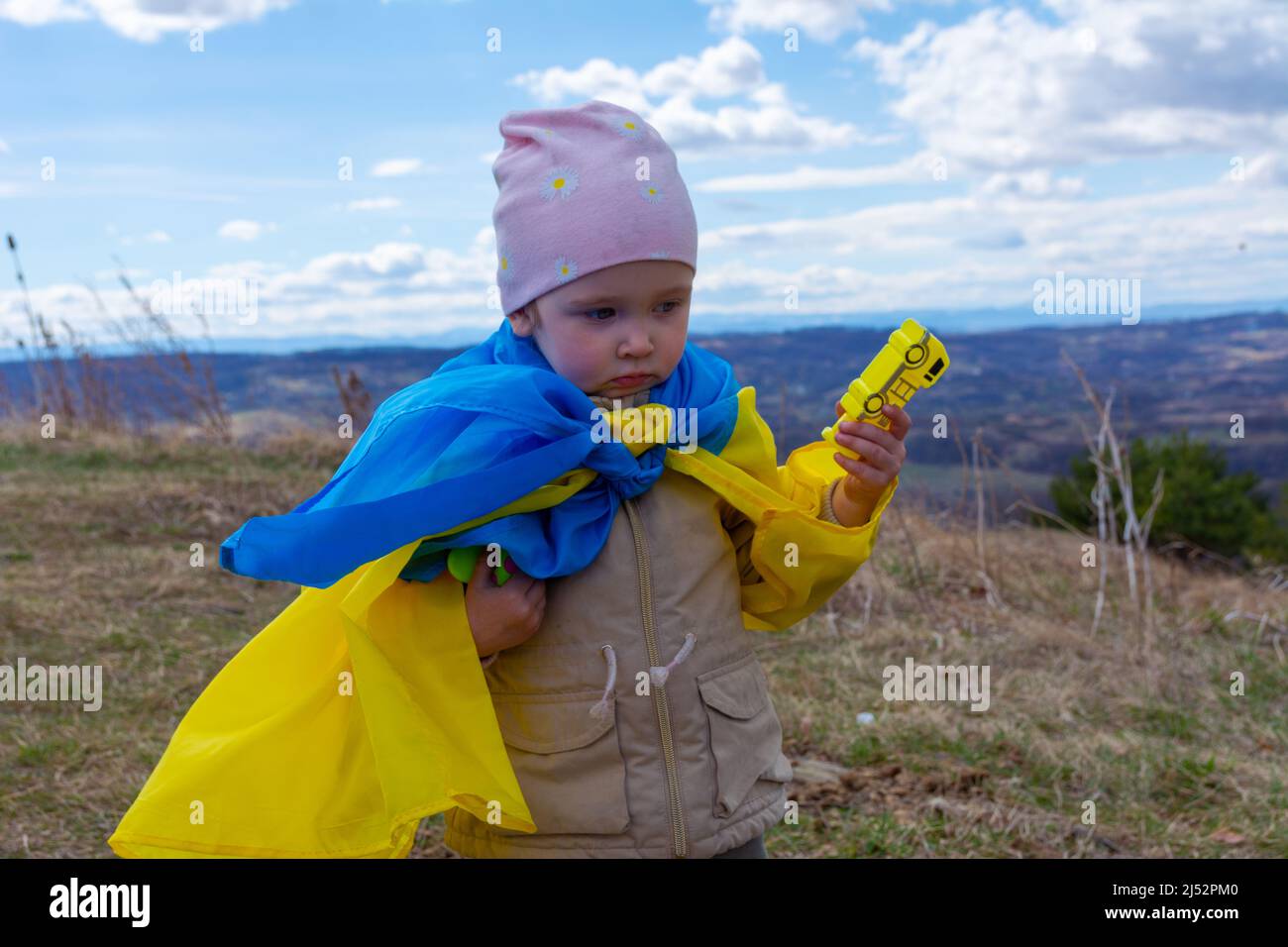 A baby girl with a flag of Ukraine against the hills and Ukrainian ...