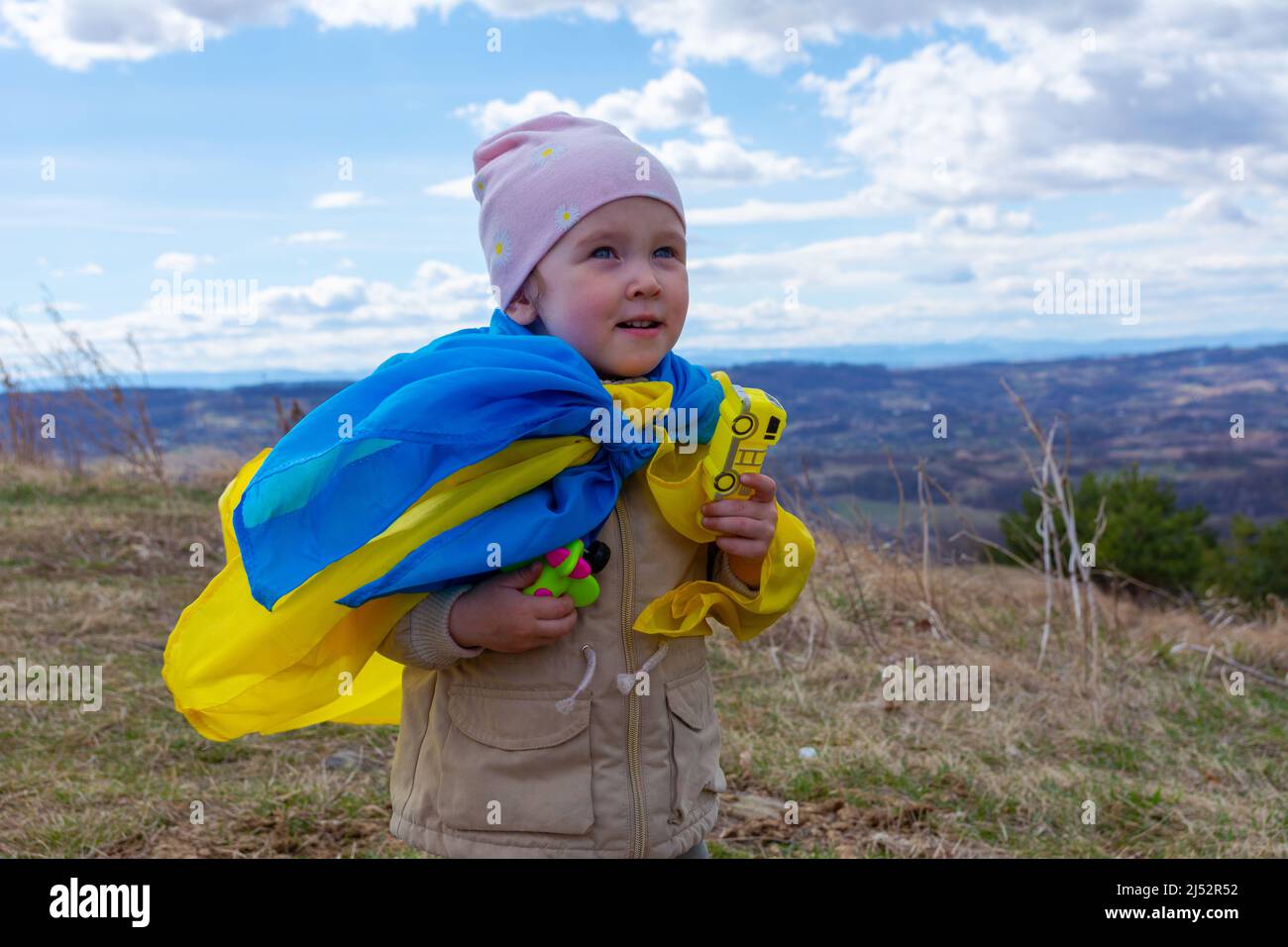 A baby girl with a flag of Ukraine against the hills and Ukrainian ...