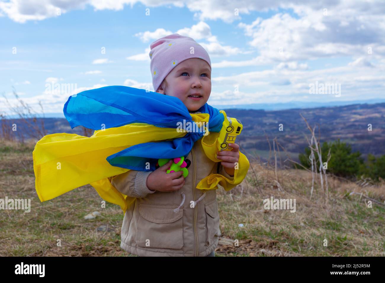 A baby girl with a flag of Ukraine against the hills and Ukrainian ...