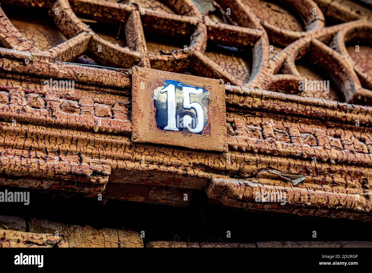 Vintage plate on the house with the number 15. Cracked brown paint and ...