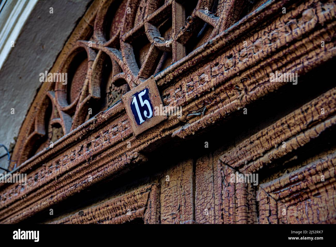 Vintage plate on the house with the number 15. Cracked brown paint and ...
