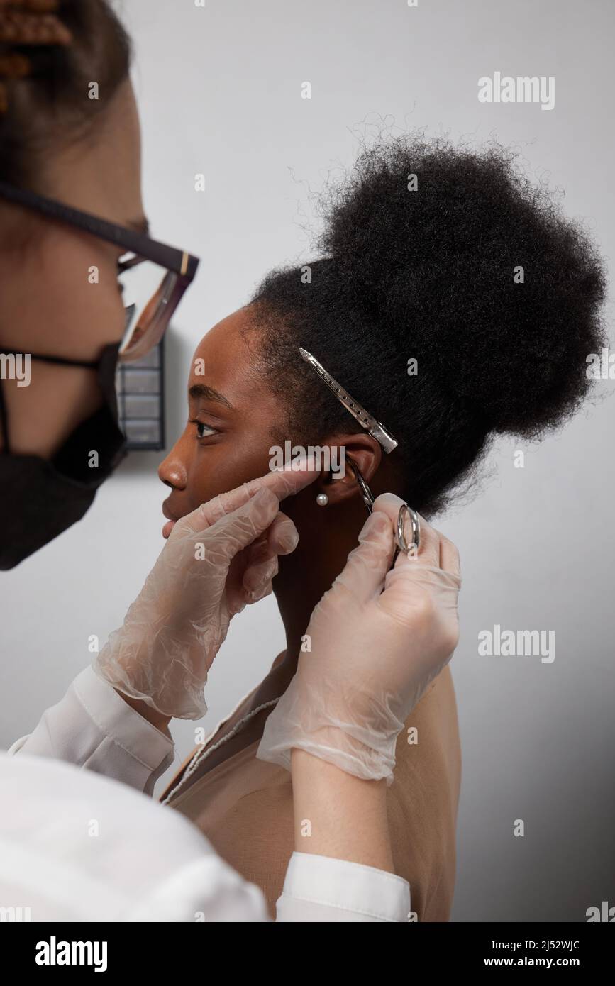 Close up of woman's ear with pierced on her ear for treatment of the ...