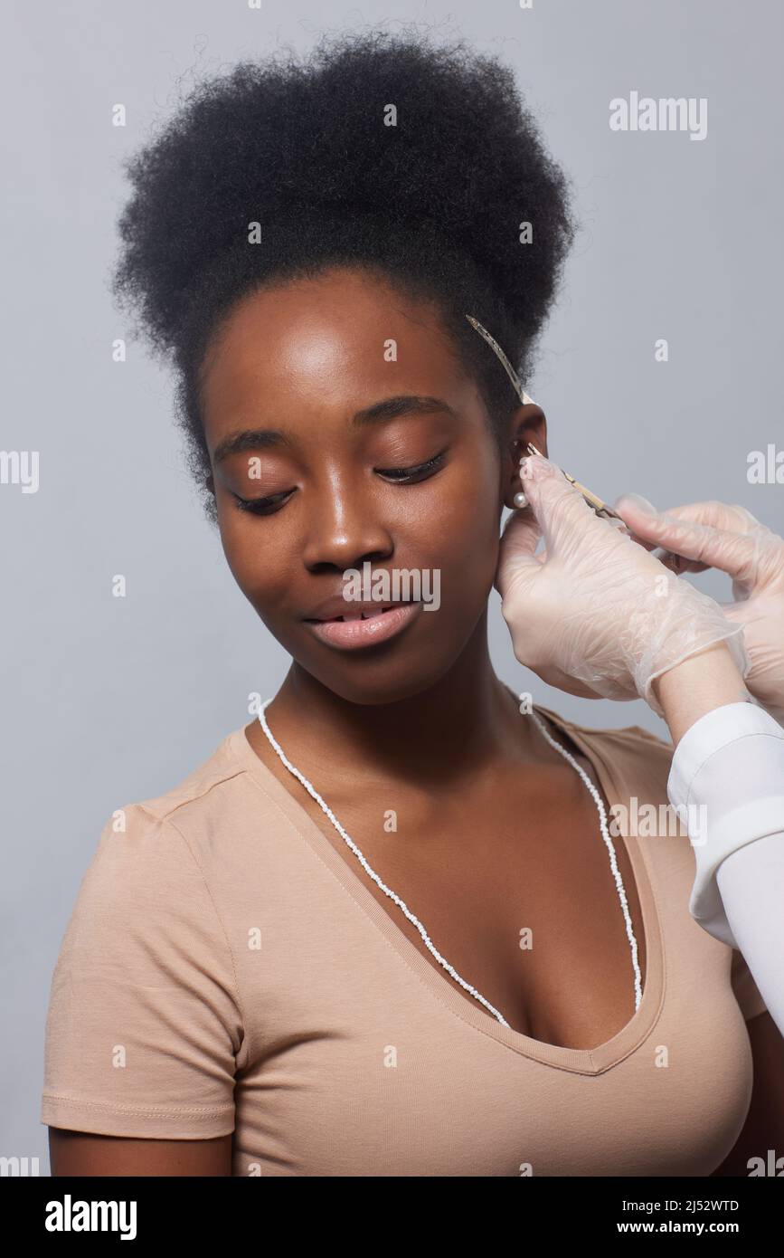Close up of woman's ear with pierced on her ear for treatment of the ...