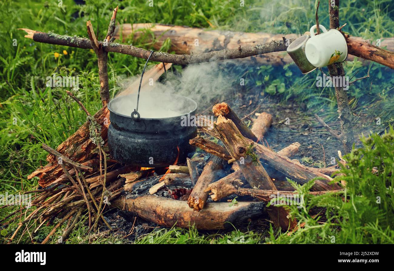 Cooking in field conditions, boiling pot at the campfire on picnic ...