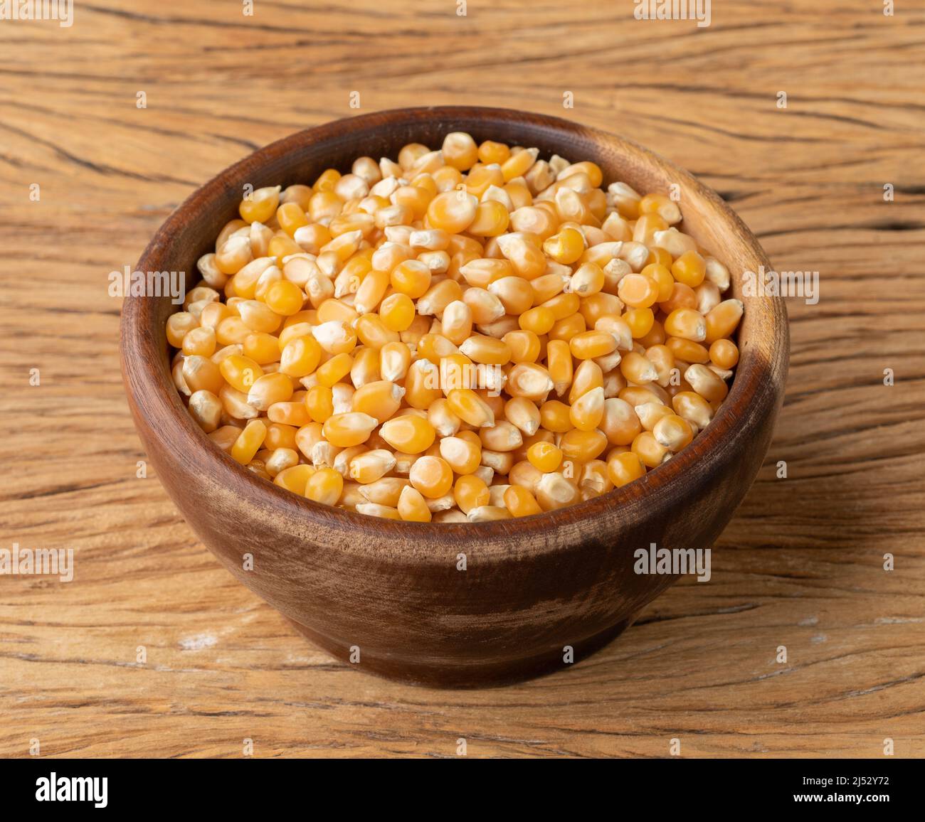 Dried corn or popcorn grains in a bowl over wooden table Stock Photo ...
