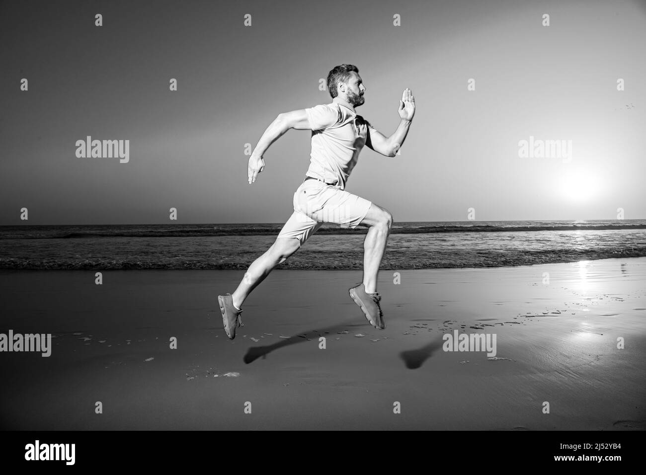 Man running on the beach at sunset. Guy runner jogger running. Dynamic ...