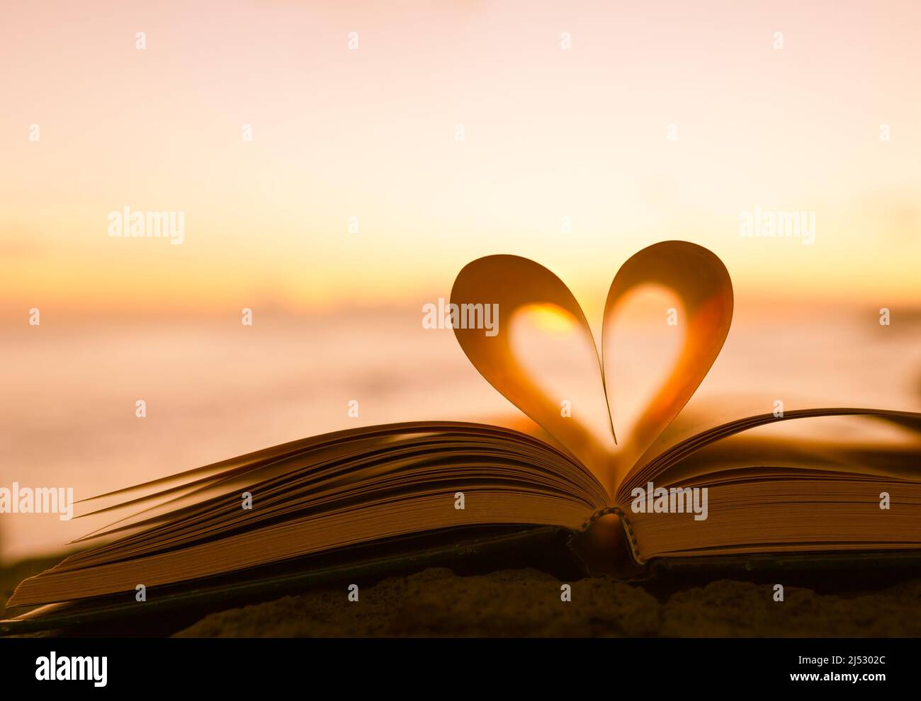 Heart from a book page against a beautiful sunset Stock Photo - Alamy