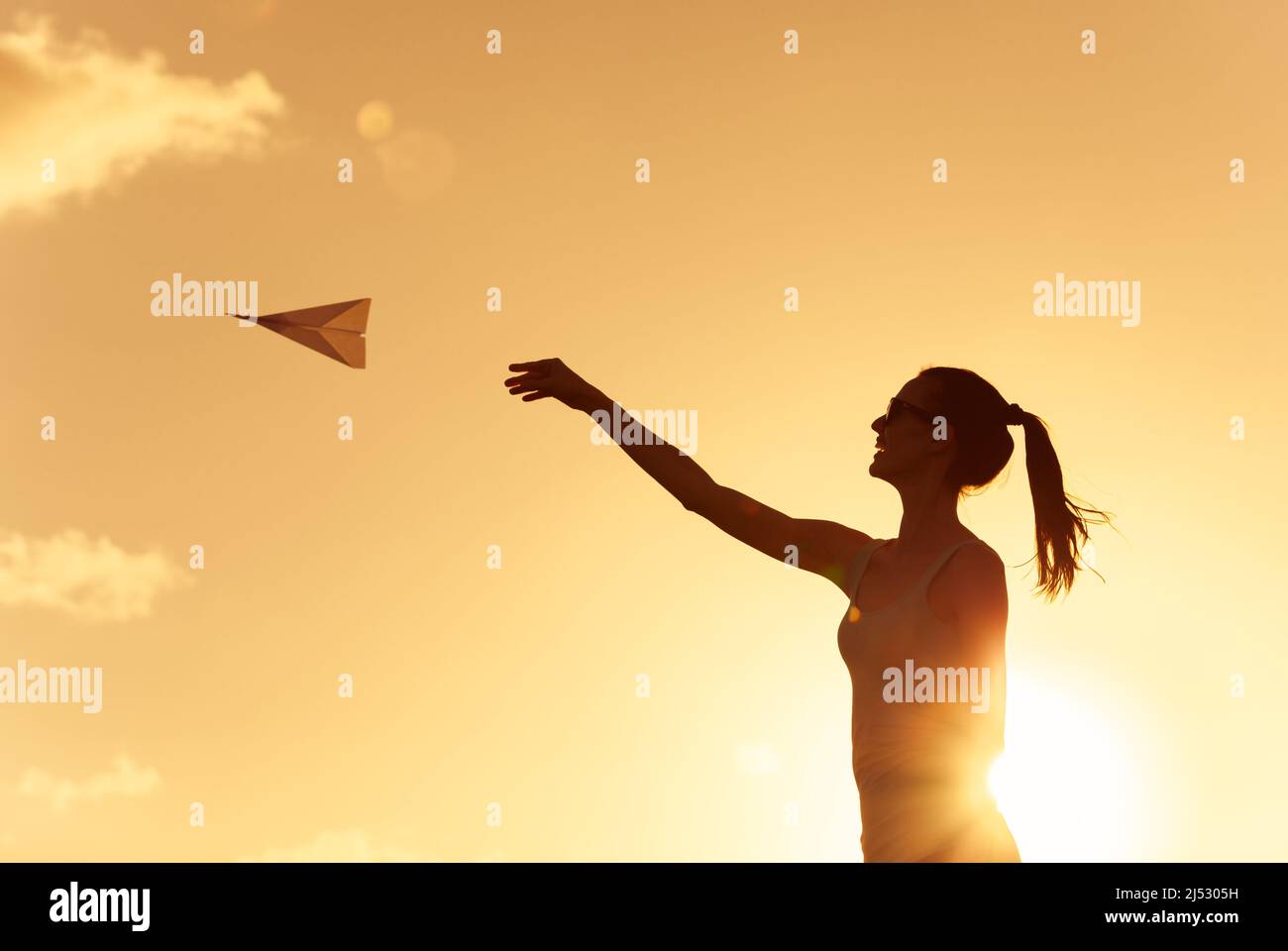 Taking flight. Female throwing paper airplane into the sky Stock Photo ...