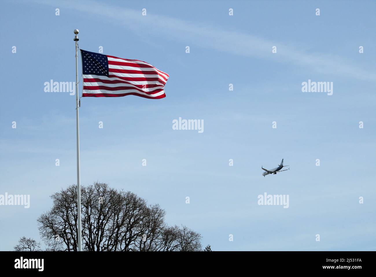 American flag at Fort Vancouver with an Alaskan Airlines plane in the ...