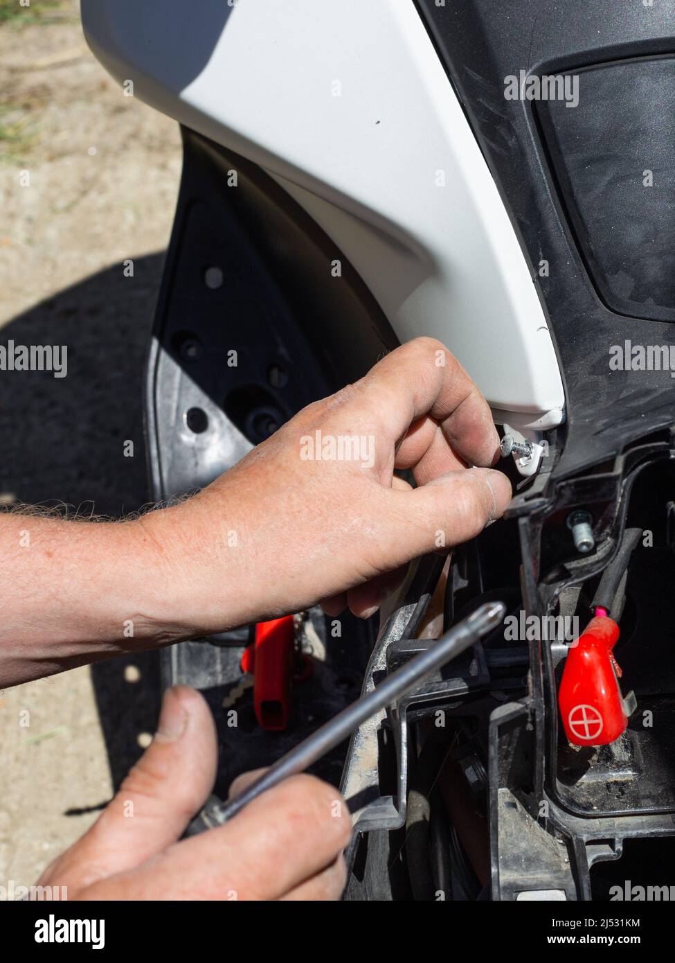 Repair and maintenance of motorcycles. The mechanic with a screwdriver ...