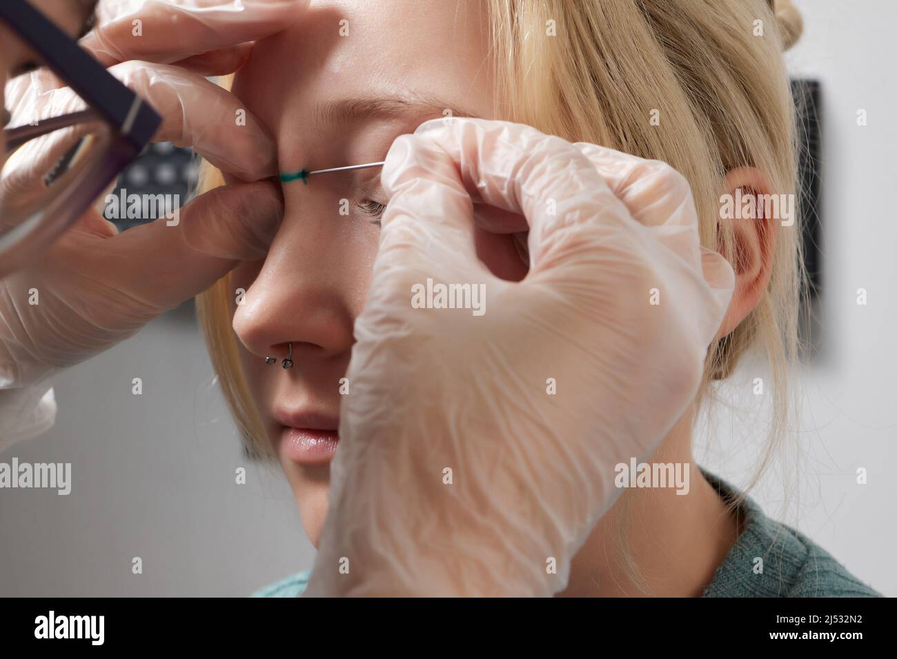 Nose Bridge Piercing Professional holding the jewel of piercing day ...