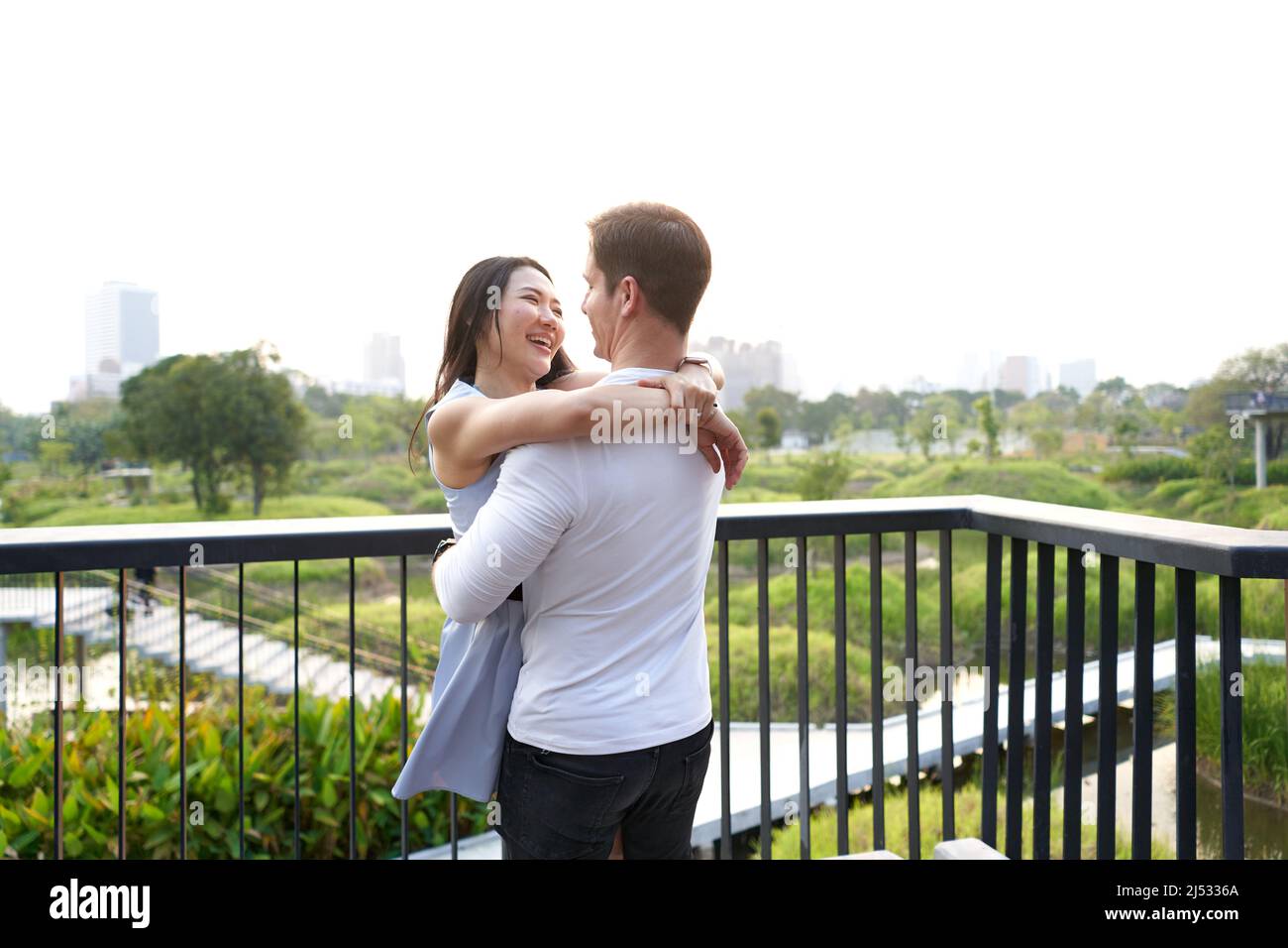 multicultural couple in love cuddling in a park at sunset Stock Photo ...