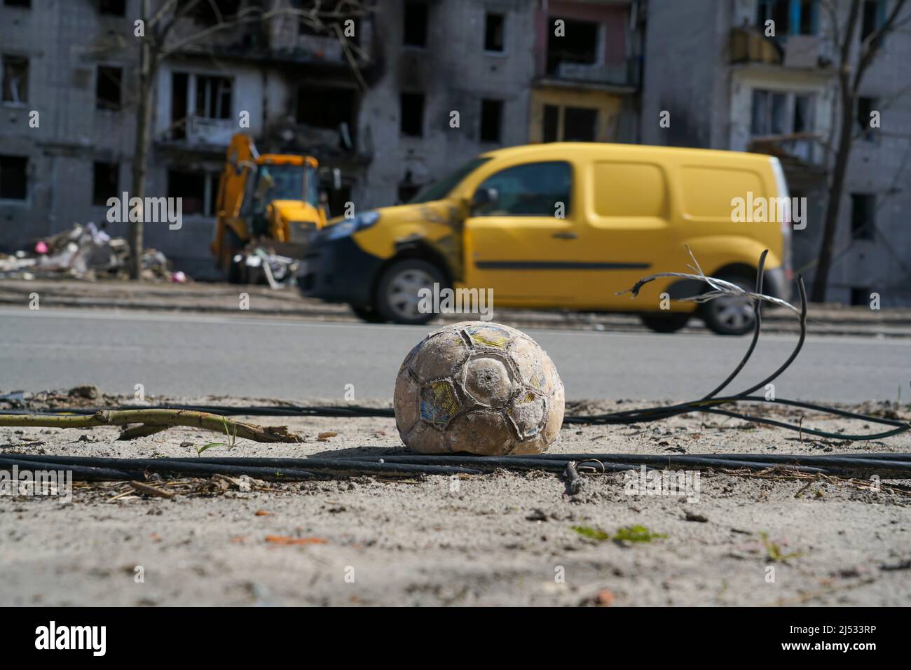 A children's soccer ball lies near the road against a building ...