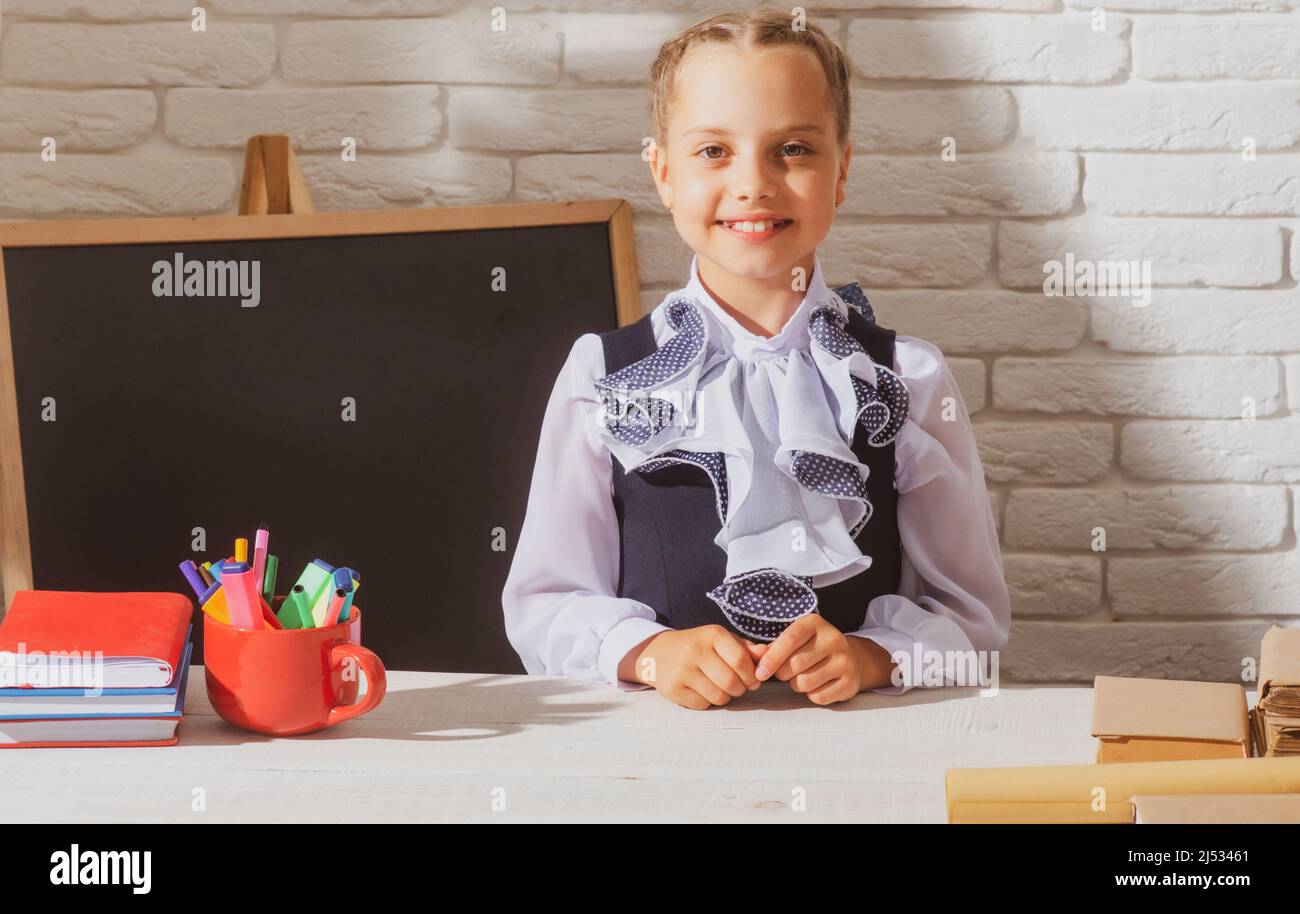 Smiling school girl wearing school uniform in classroom at school ...
