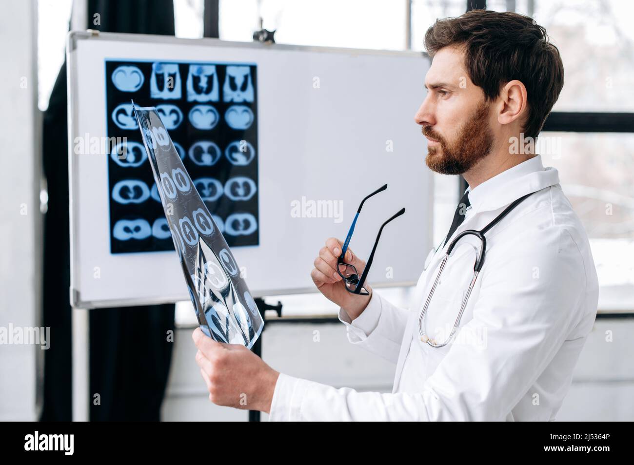Smart concentrated Caucasian doctor in a medical uniform, a ...