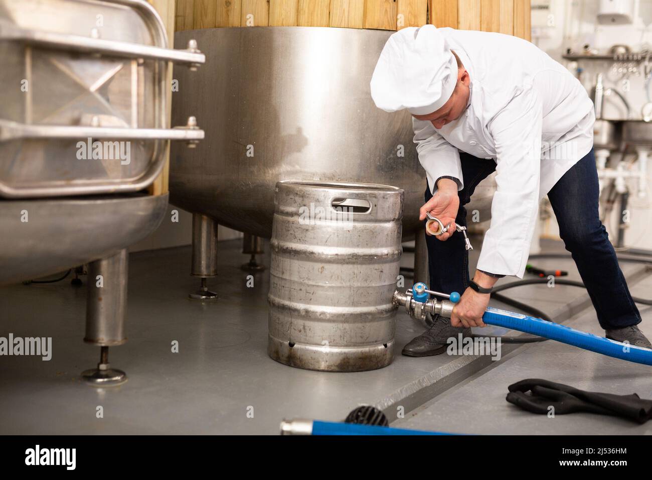 Brewer connecting hose to keg to fill with beer in brewery Stock Photo ...