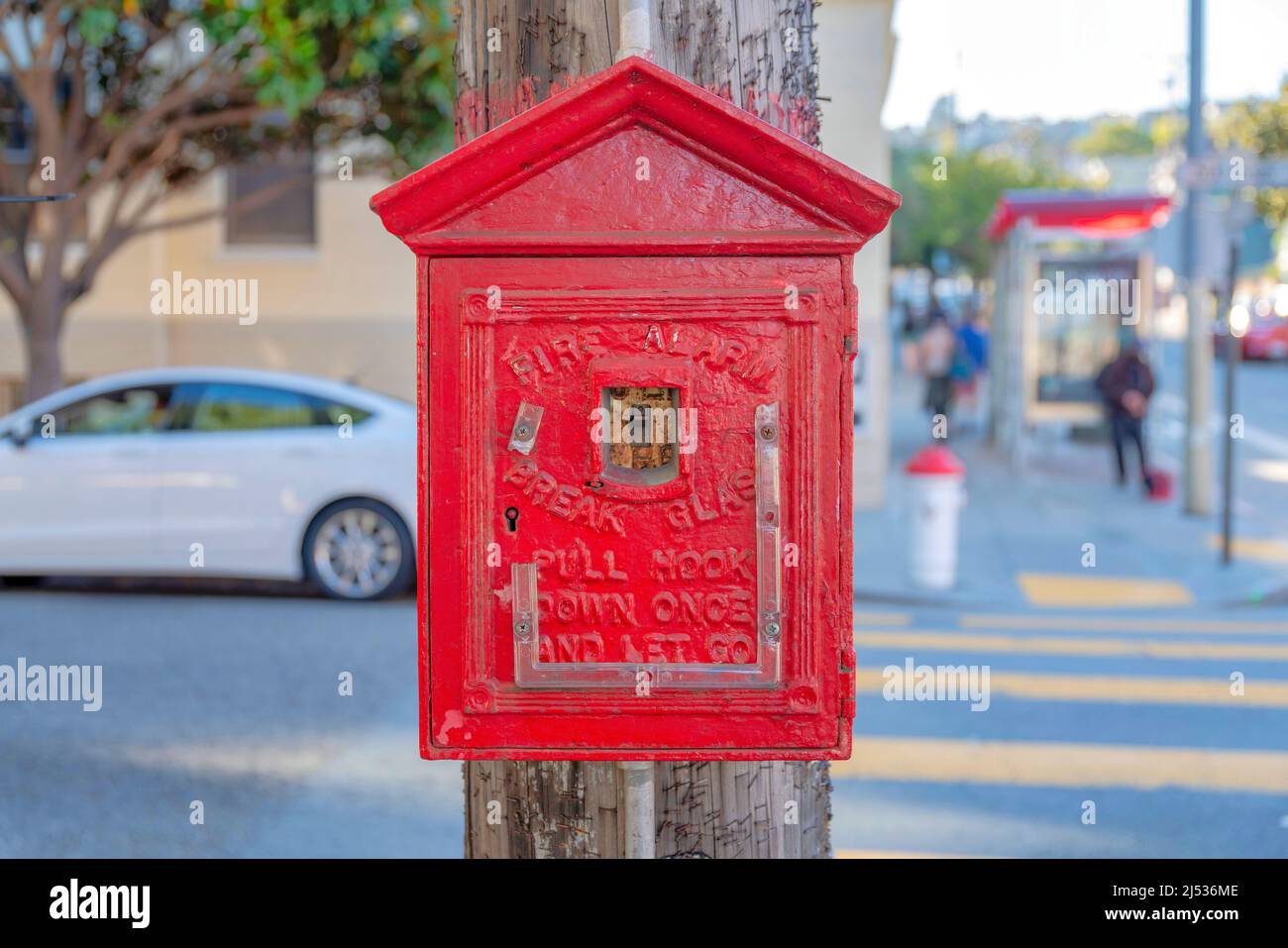 Fire alarm inside the small red house on a wooden post at crosswalk in ...