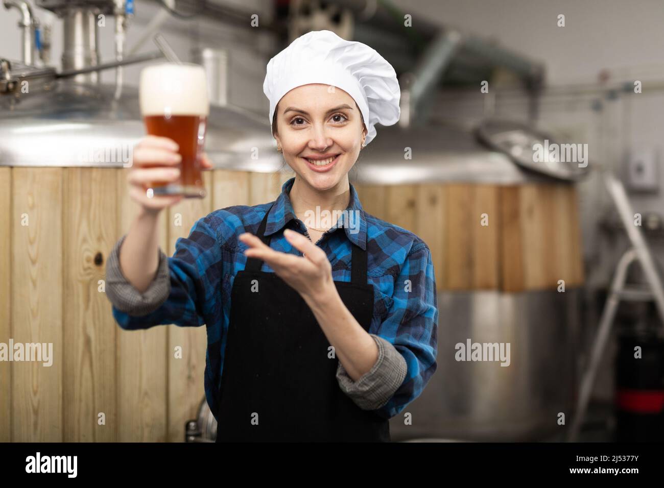 Successful female brewmaster holding glass of foamy ale Stock Photo - Alamy