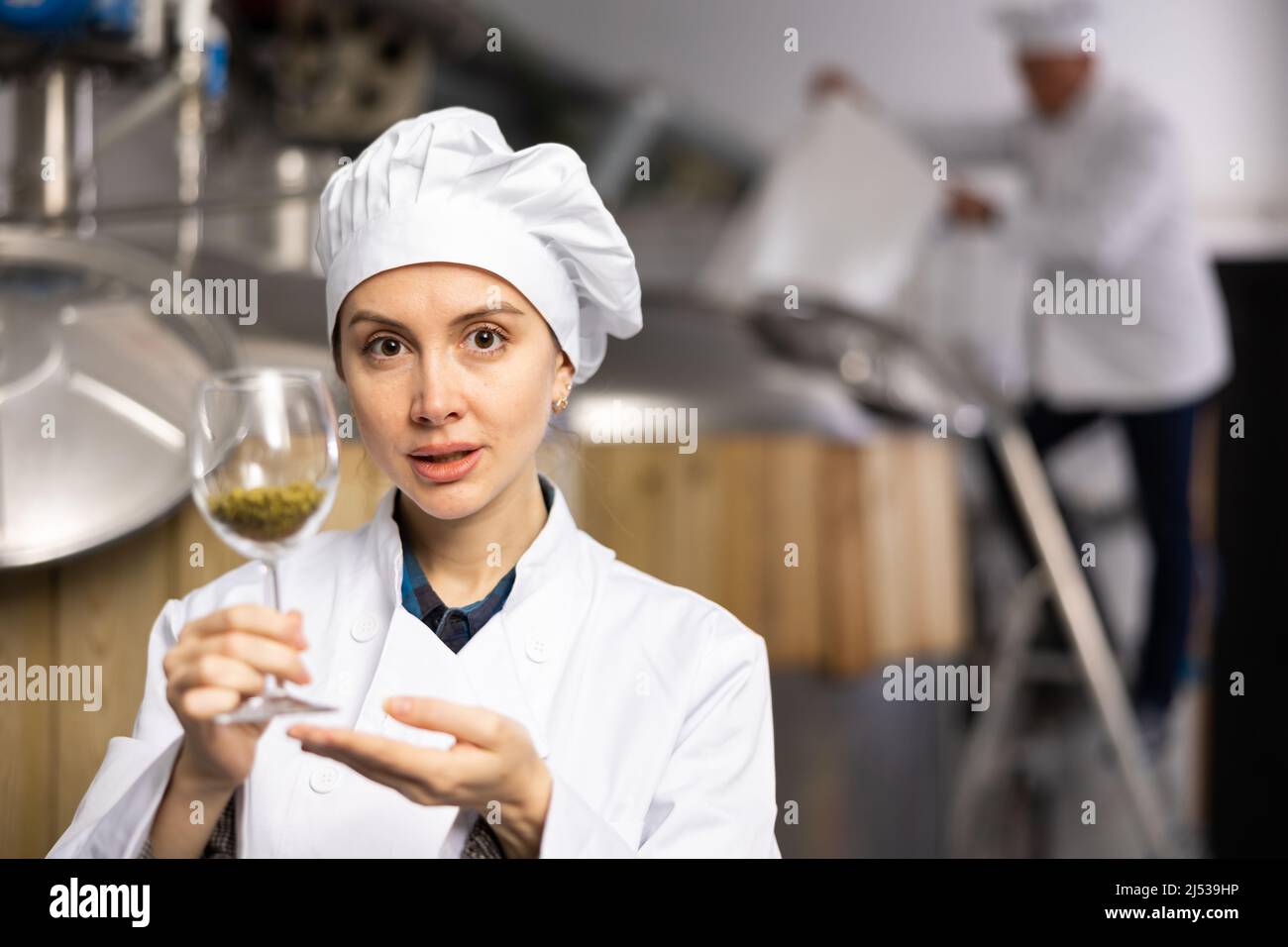 Successful female brewmaster showing hop pellets in glass Stock Photo ...