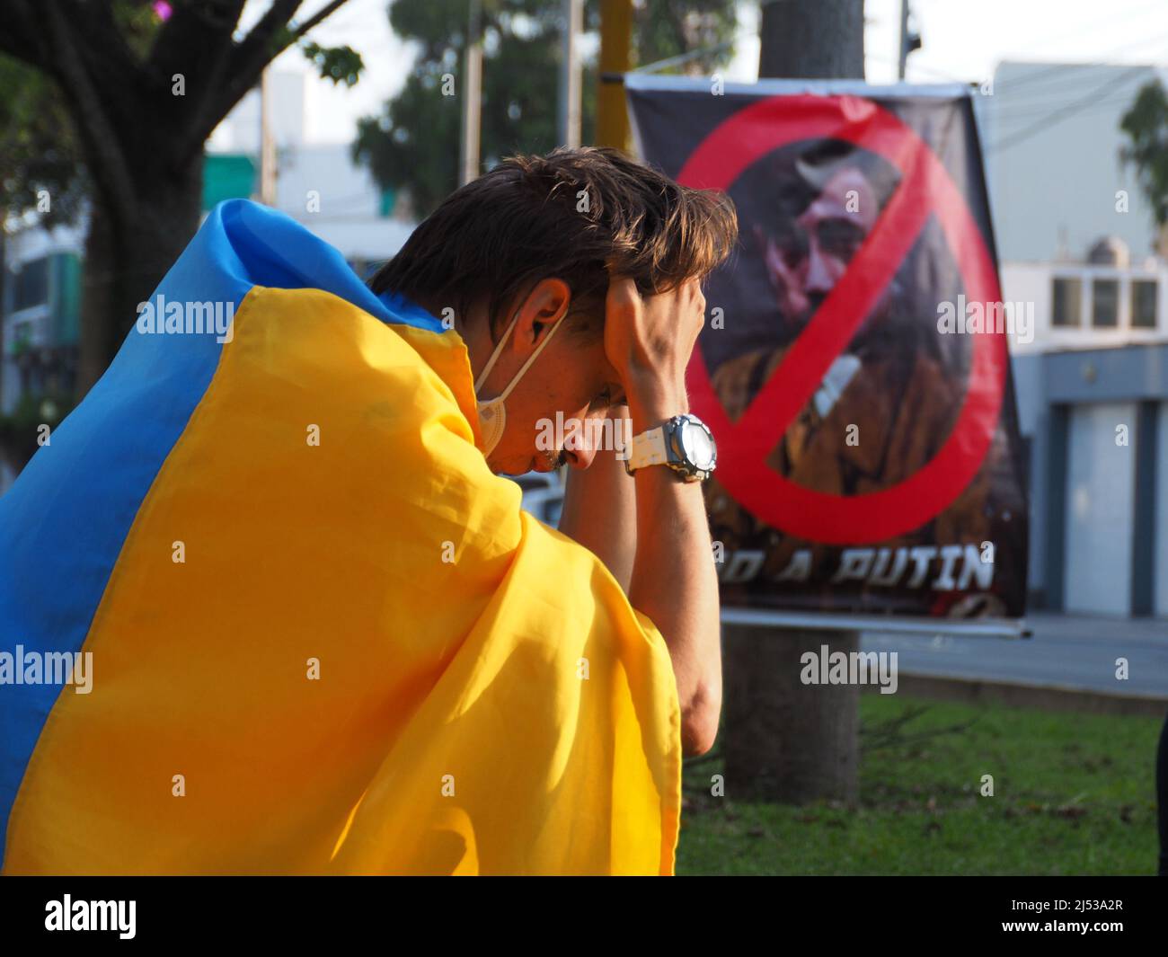 A distraught Ukrainian sits in front of a banner in which reads "Not to ...