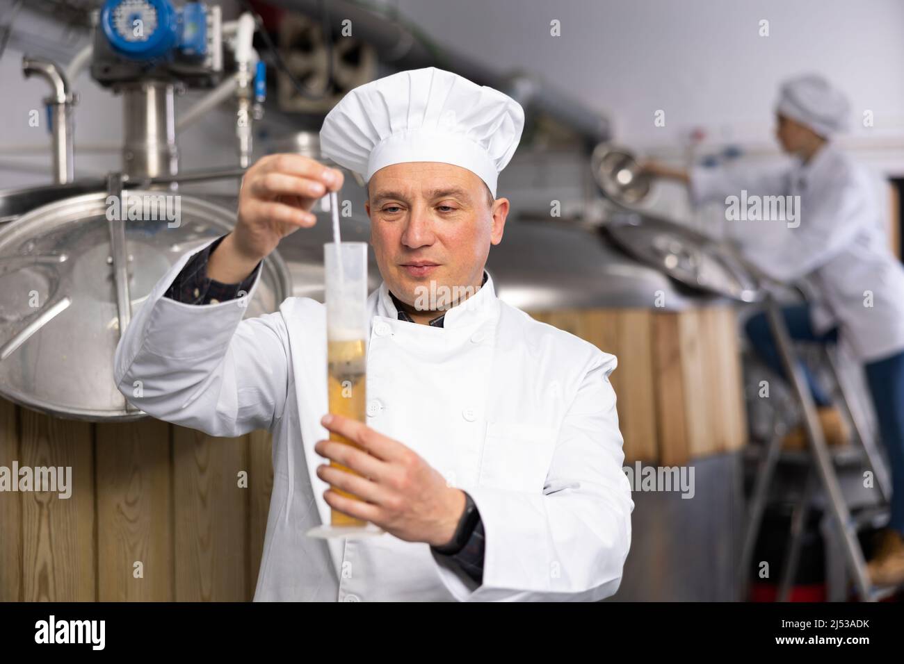 Man brewmaster measuring beer with alcoholometer Stock Photo - Alamy