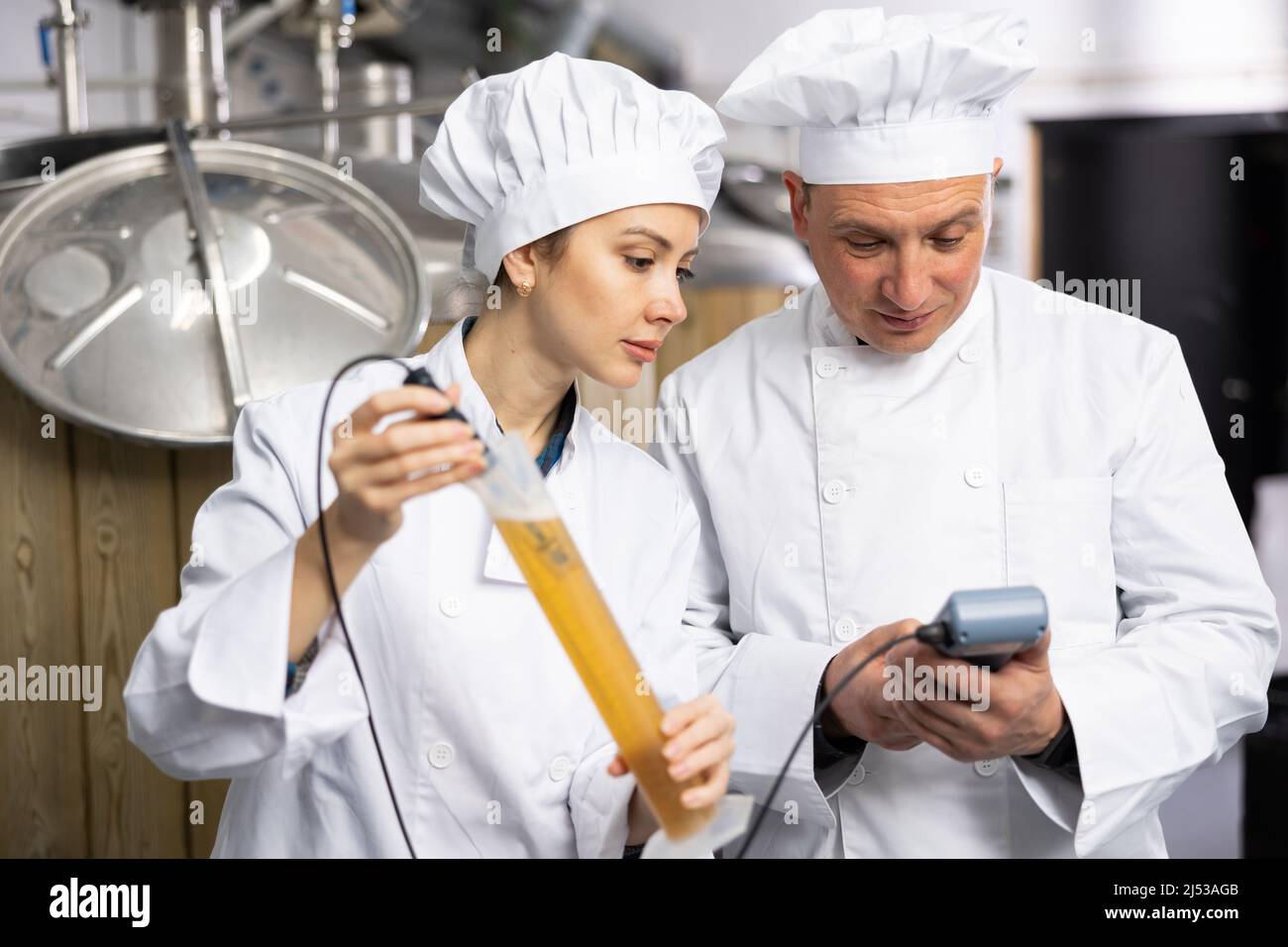 Woman and man check the amount of alcohol in beer with an alcohol meter ...