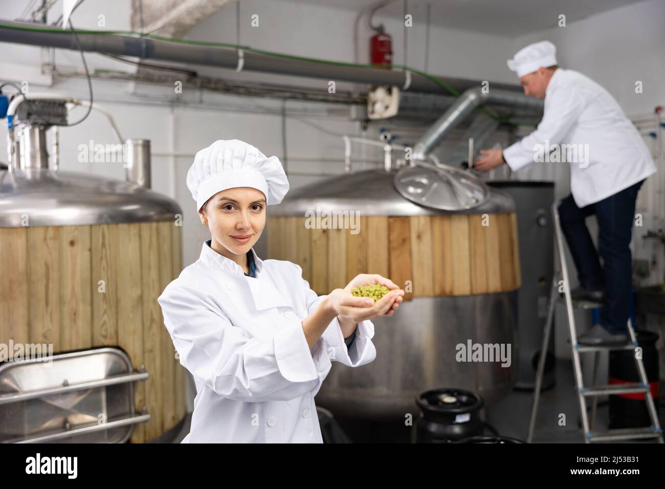 Smiling female brewmaster holding handful of pelletized hops Stock ...
